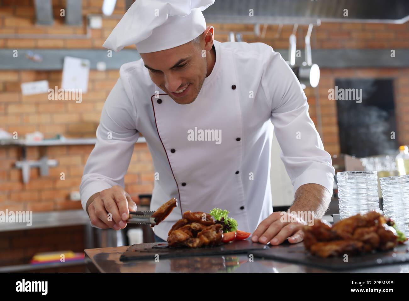 Professional chef with delicious fried chicken wings in restaurant ...