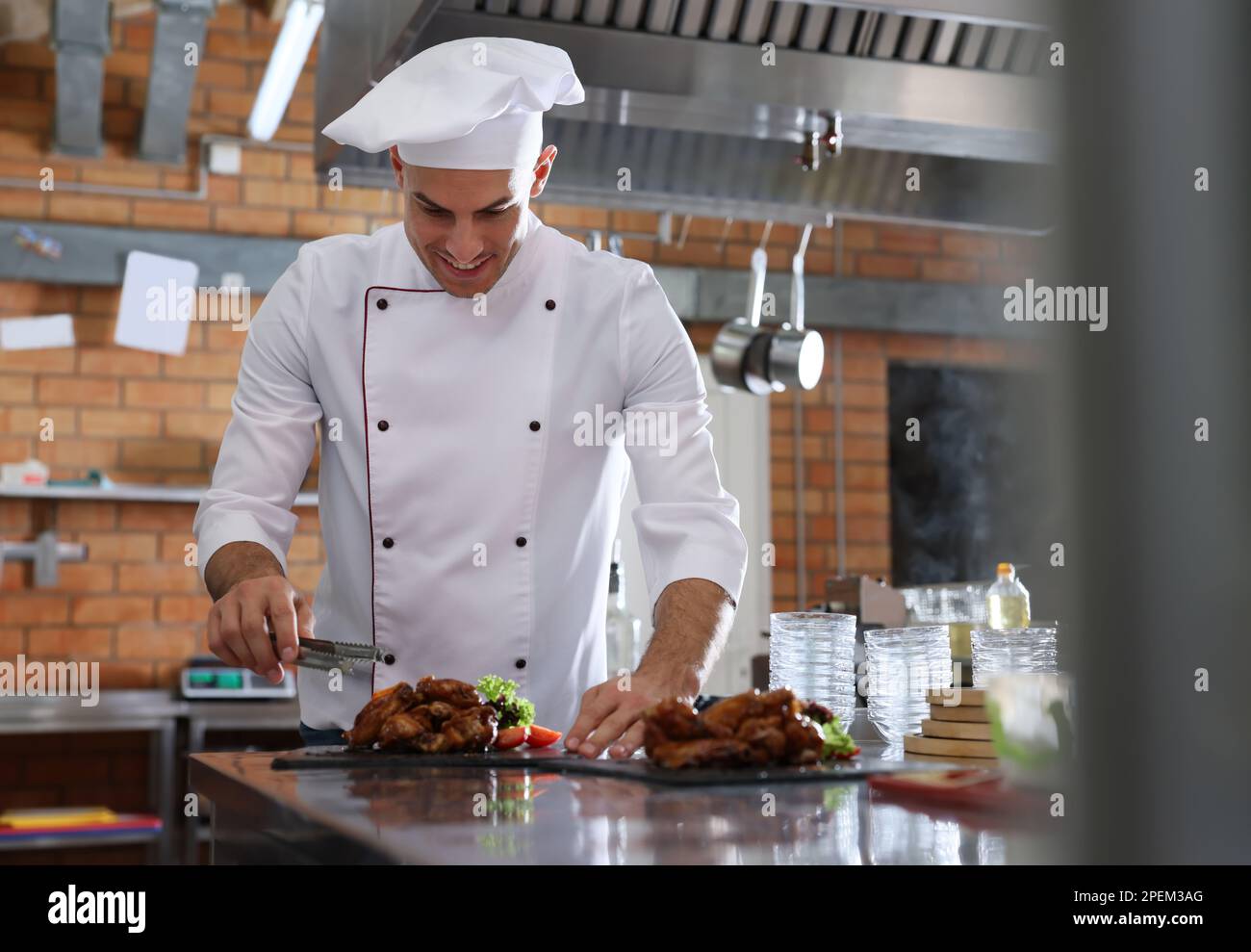 Professional chef with delicious fried chicken wings in restaurant ...