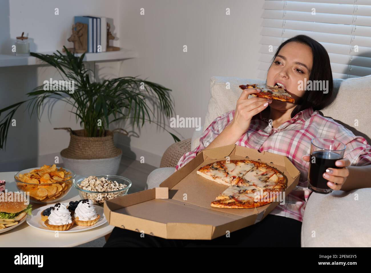 Overweight woman eating pizza with cola on sofa at home Stock Photo - Alamy