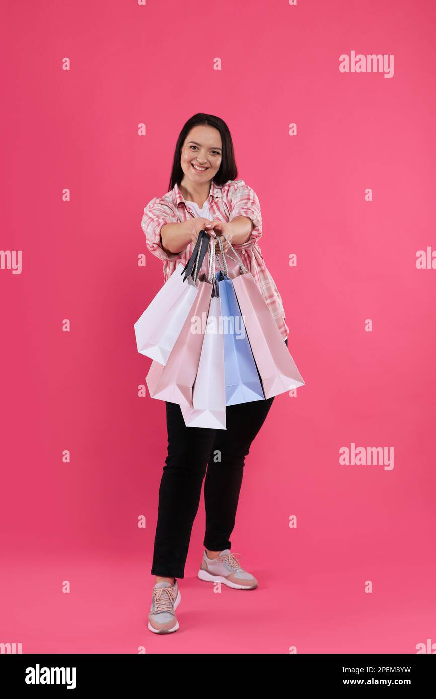 Beautiful overweight woman with shopping bags on pink background Stock ...