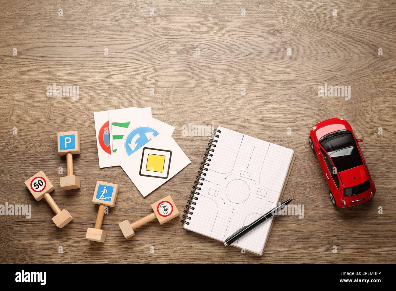 Many different road signs, notebook and toy car on wooden background ...