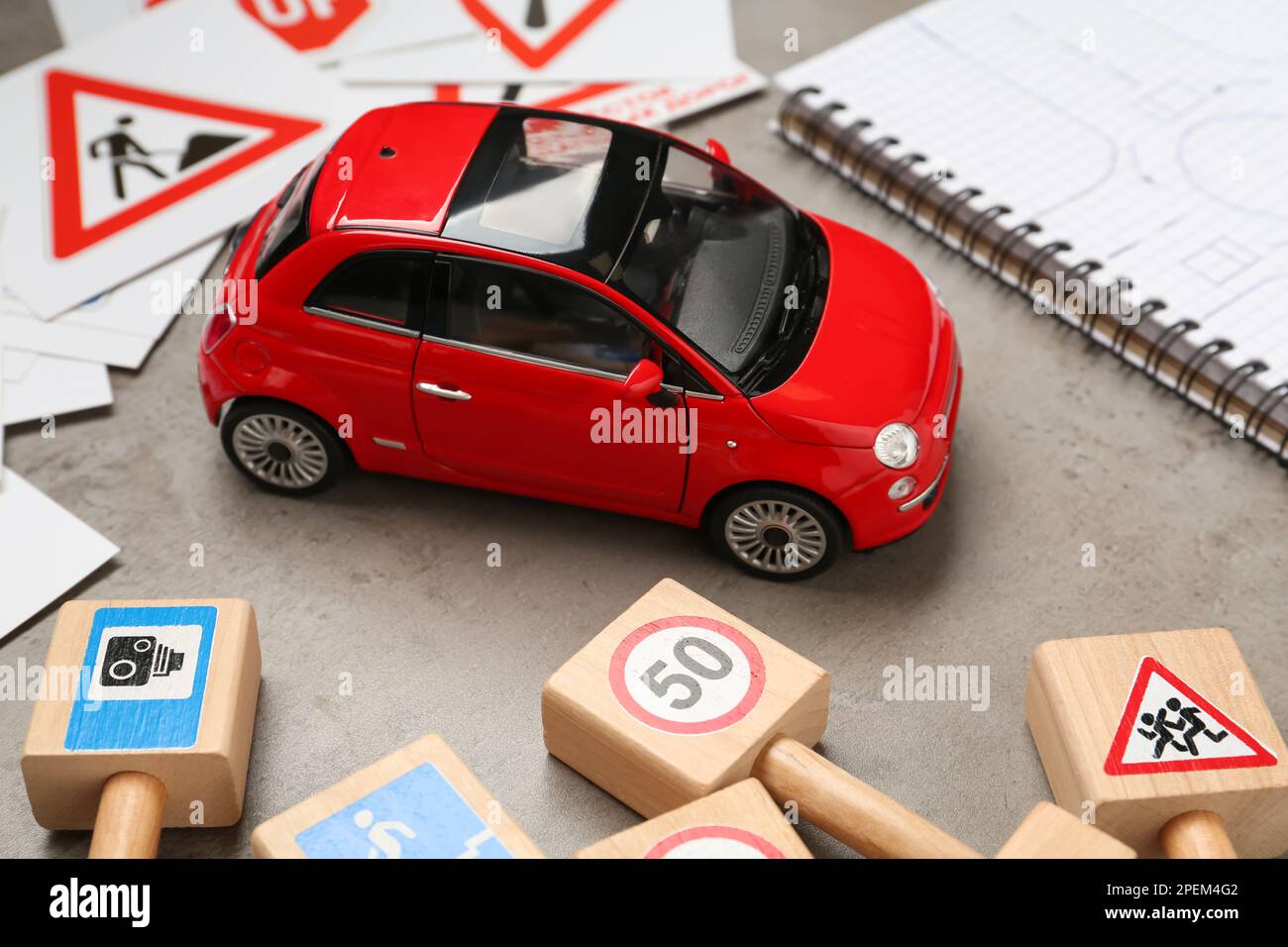 Many different road signs, notebook and toy car on grey table, closeup ...
