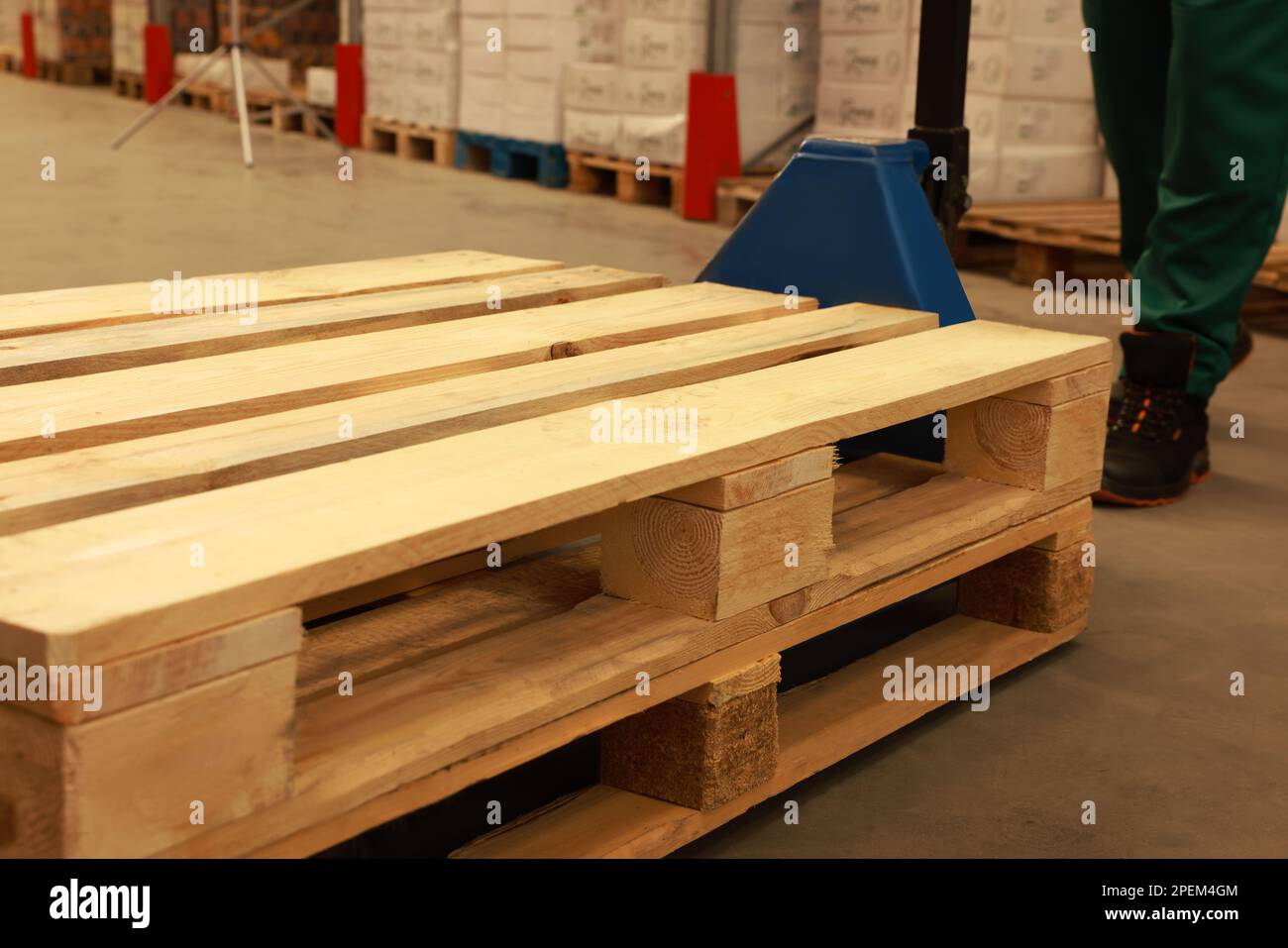 Worker moving wooden pallets with manual forklift in warehouse, closeup ...