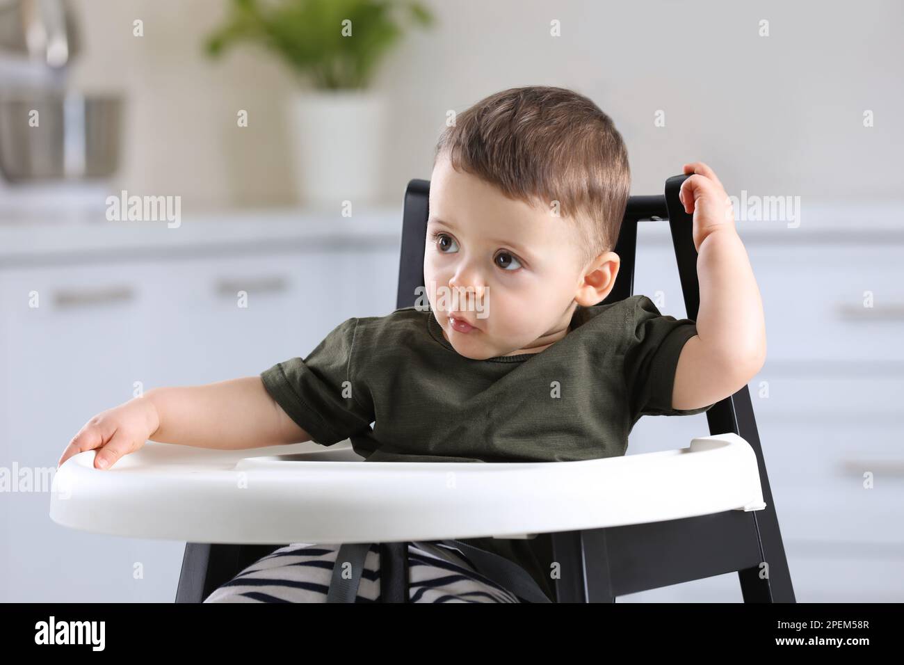 Cute little baby sitting in high chair at kitchen Stock Photo - Alamy