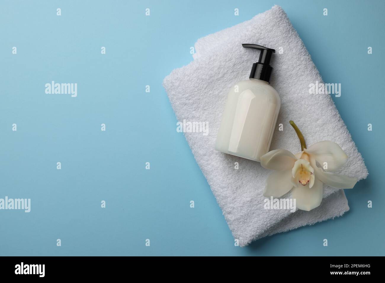 Bottle of liquid soap, towel and flower on light blue background, top ...