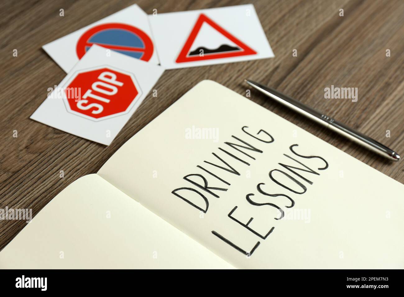 Workbook for driving lessons, pen and road signs on wooden table ...