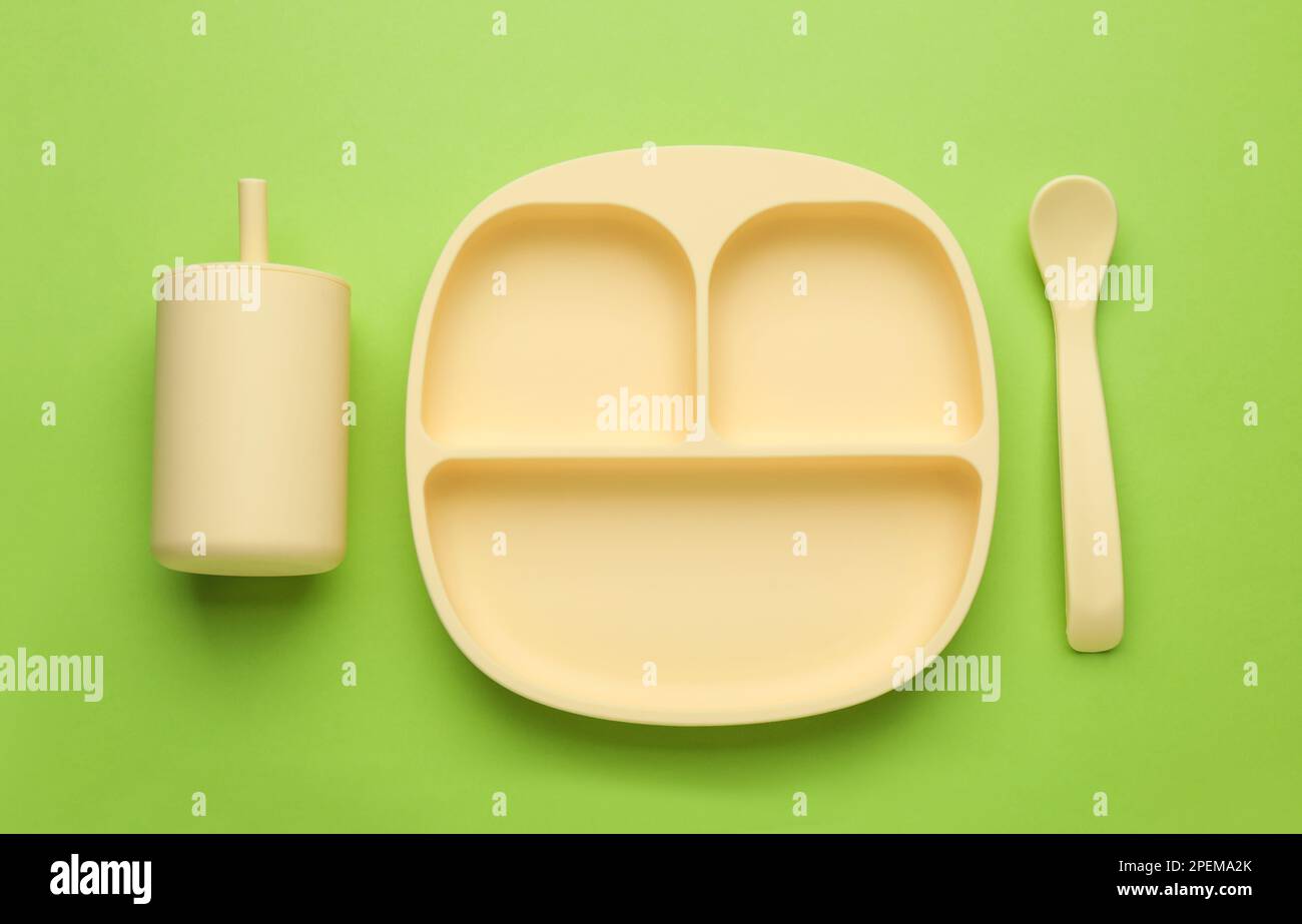 Set of plastic dishware on light green background, flat lay. Serving ...