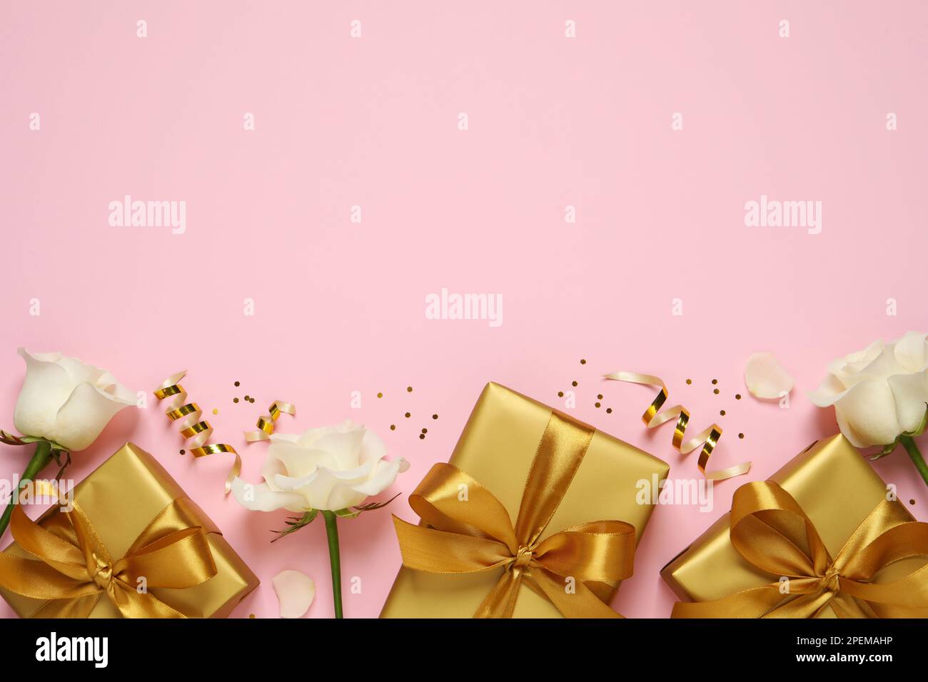 Golden gift boxes, white roses, confetti and streamers on pink ...