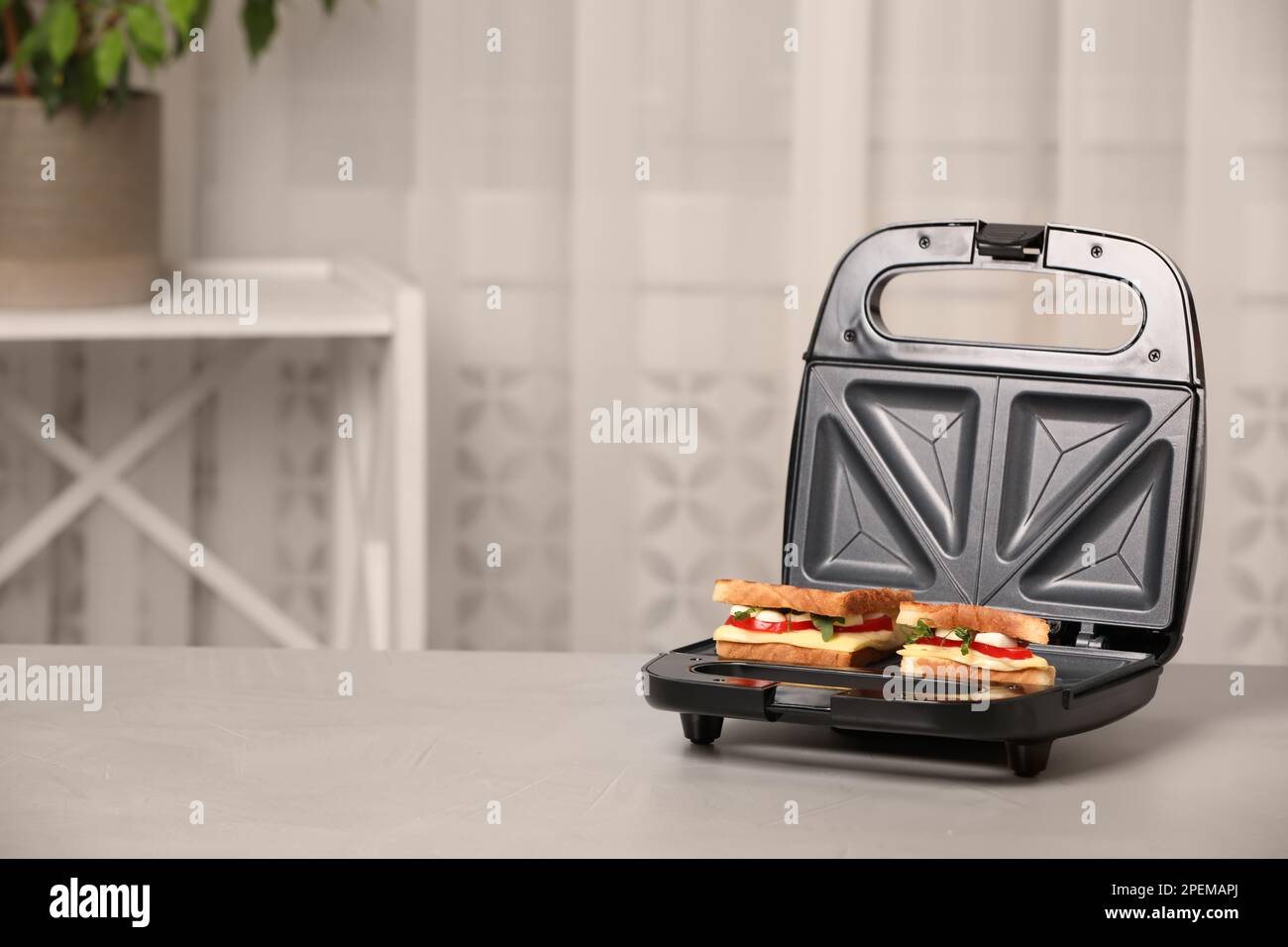 Modern grill maker with sandwiches on light grey table indoors, space ...