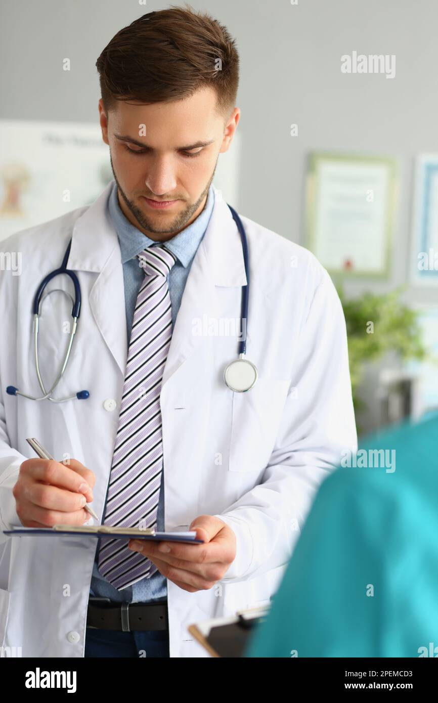 Male doctor filling out patient medical form in clinic Stock Photo - Alamy