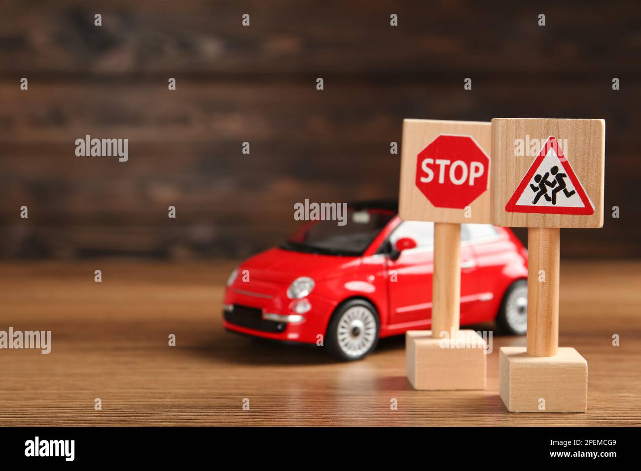 Miniature road signs and car on wooden table, space for text. Driving ...