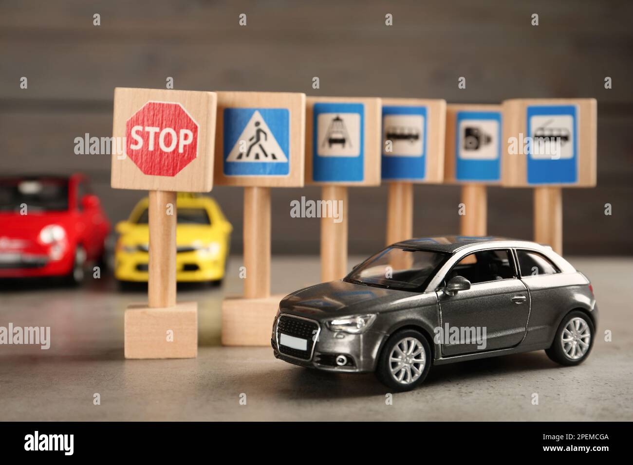 Many different miniature road signs and car on grey table. Driving ...