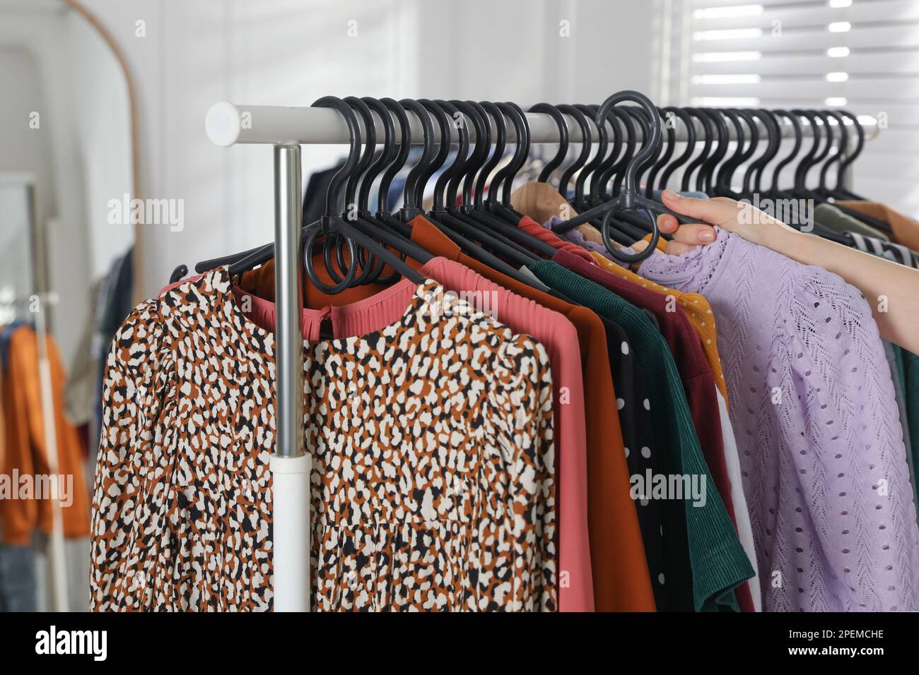Woman picking clothes from rack indoors, closeup. Fast fashion Stock ...