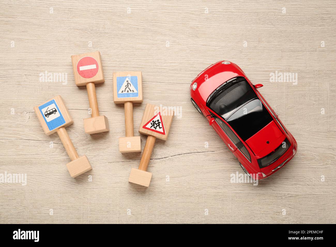 Different miniature road signs and car on wooden table, flat lay ...