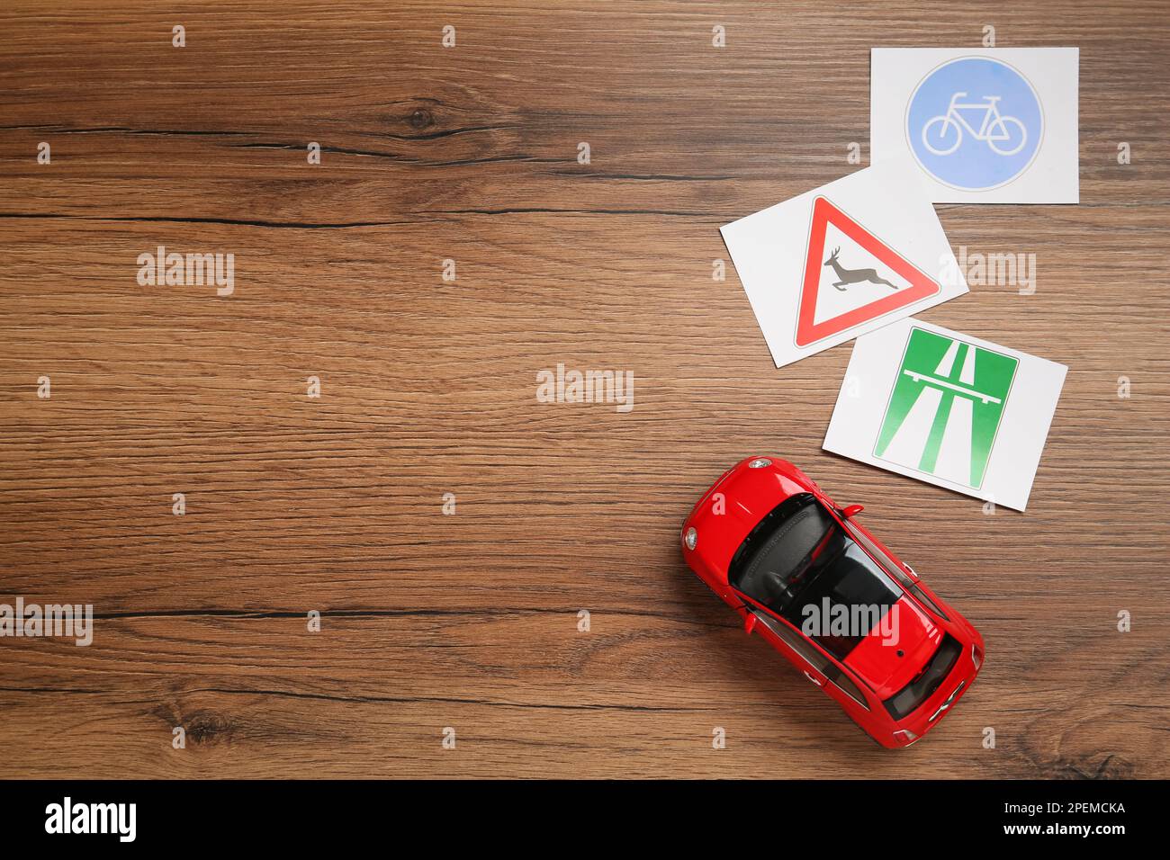 Different road sign cards and toy car on wooden table, flat lay with ...
