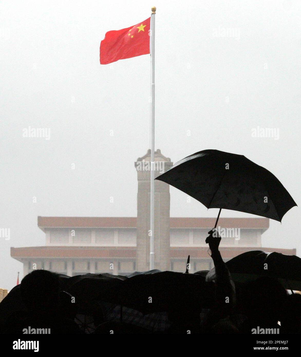 A visitor holds an umbrella above the crowd as they walk towards the ...