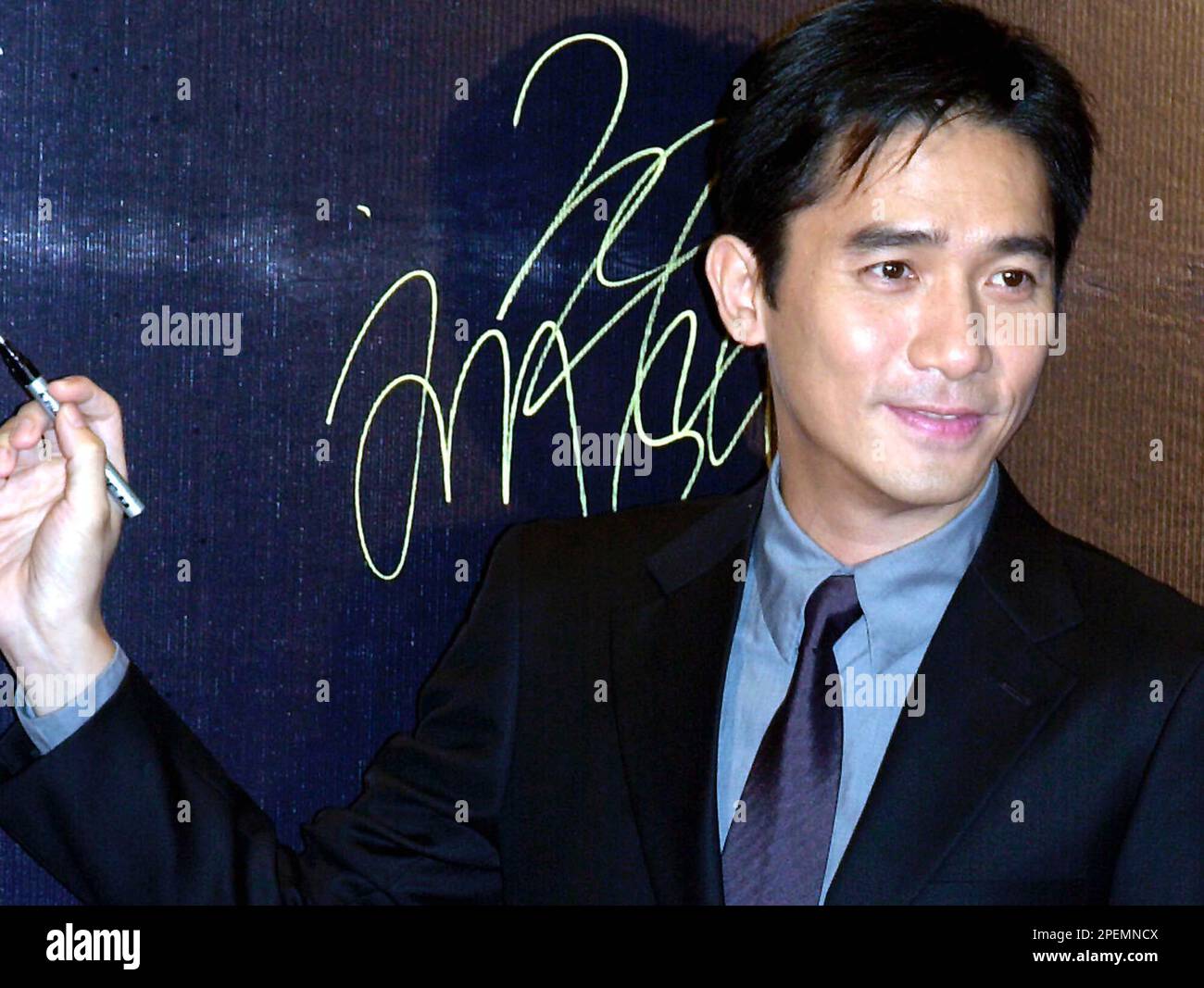 Hong Kong actor Tony Leung autographs his name on a board at a cinema ...