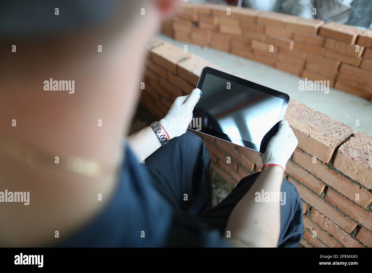 Builder stands in house under construction and holds tablet computer ...