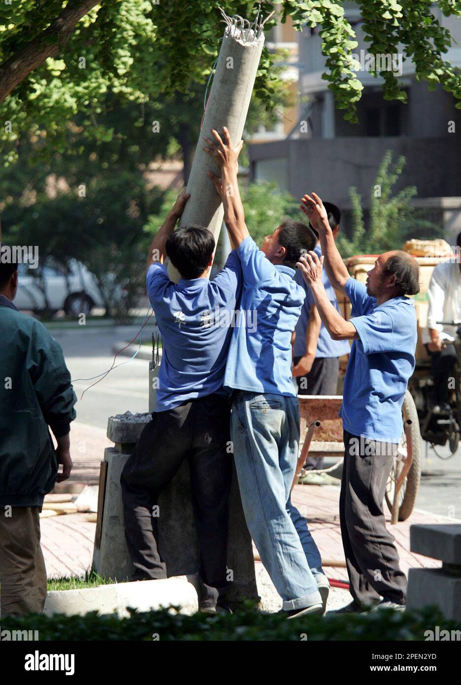 Workers pull down an old lamp post in a diplomatic compound in Beijing ...
