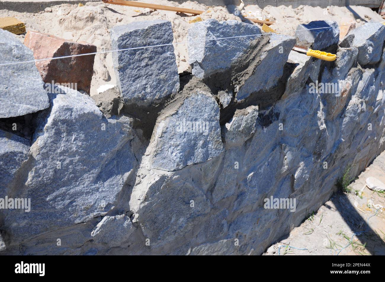 Laying wild rock blocks for house wall foundation with concrete Stock ...