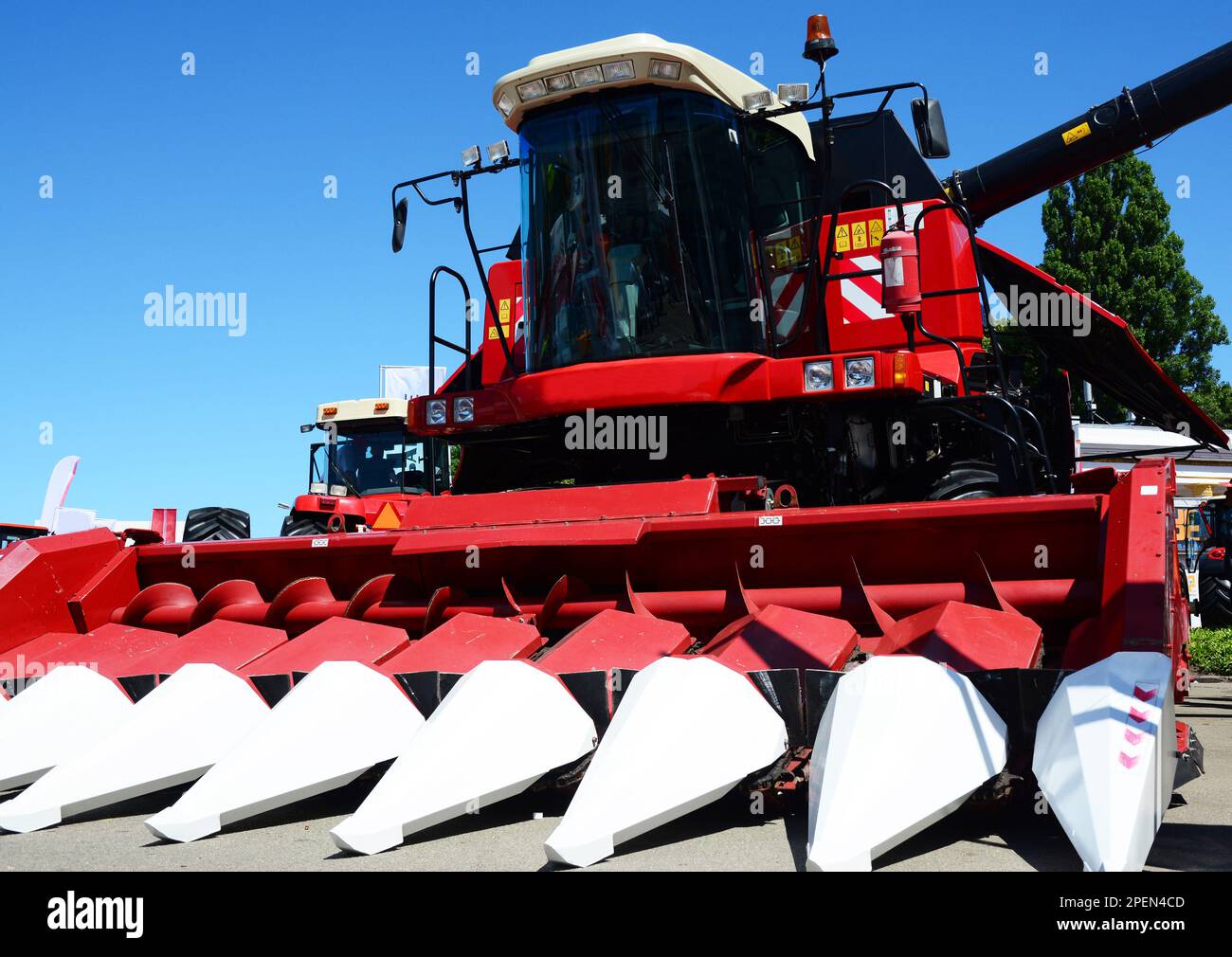 Big red combine harvester against blue sky Stock Photo - Alamy
