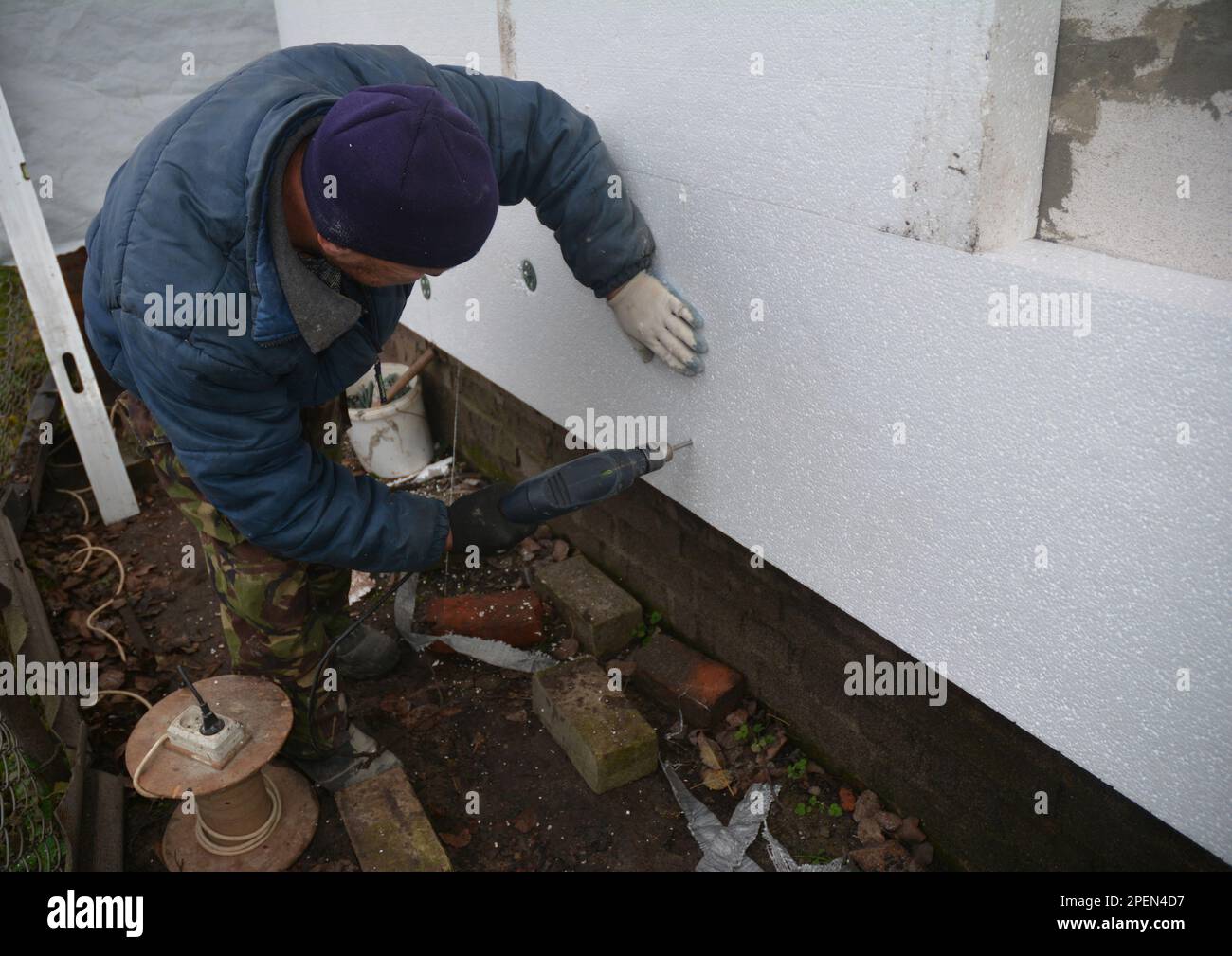 A man is insulating the house facade with polystyrene boards. Thermal ...