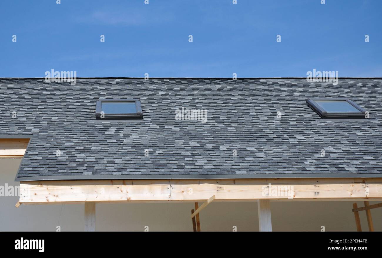 Rooftop house construction with new attic skylight windows and asphalt ...