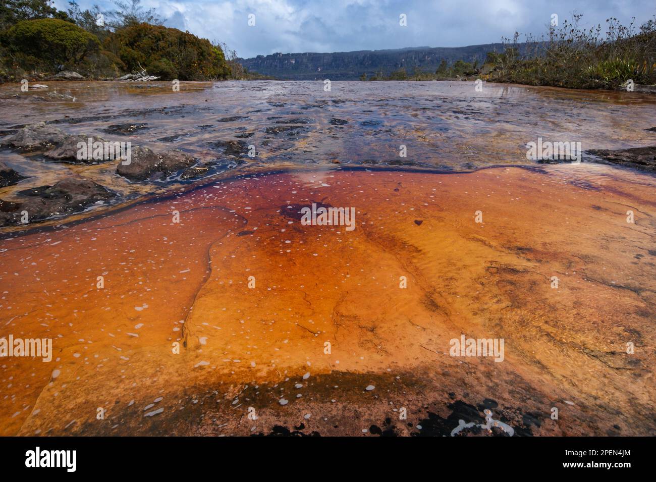 Orange and black rock structures in shallow river on the plateau of ...