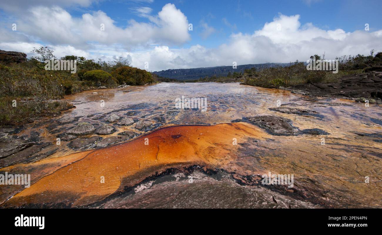 Shallow river with orange and black rock structures on the plateau of ...