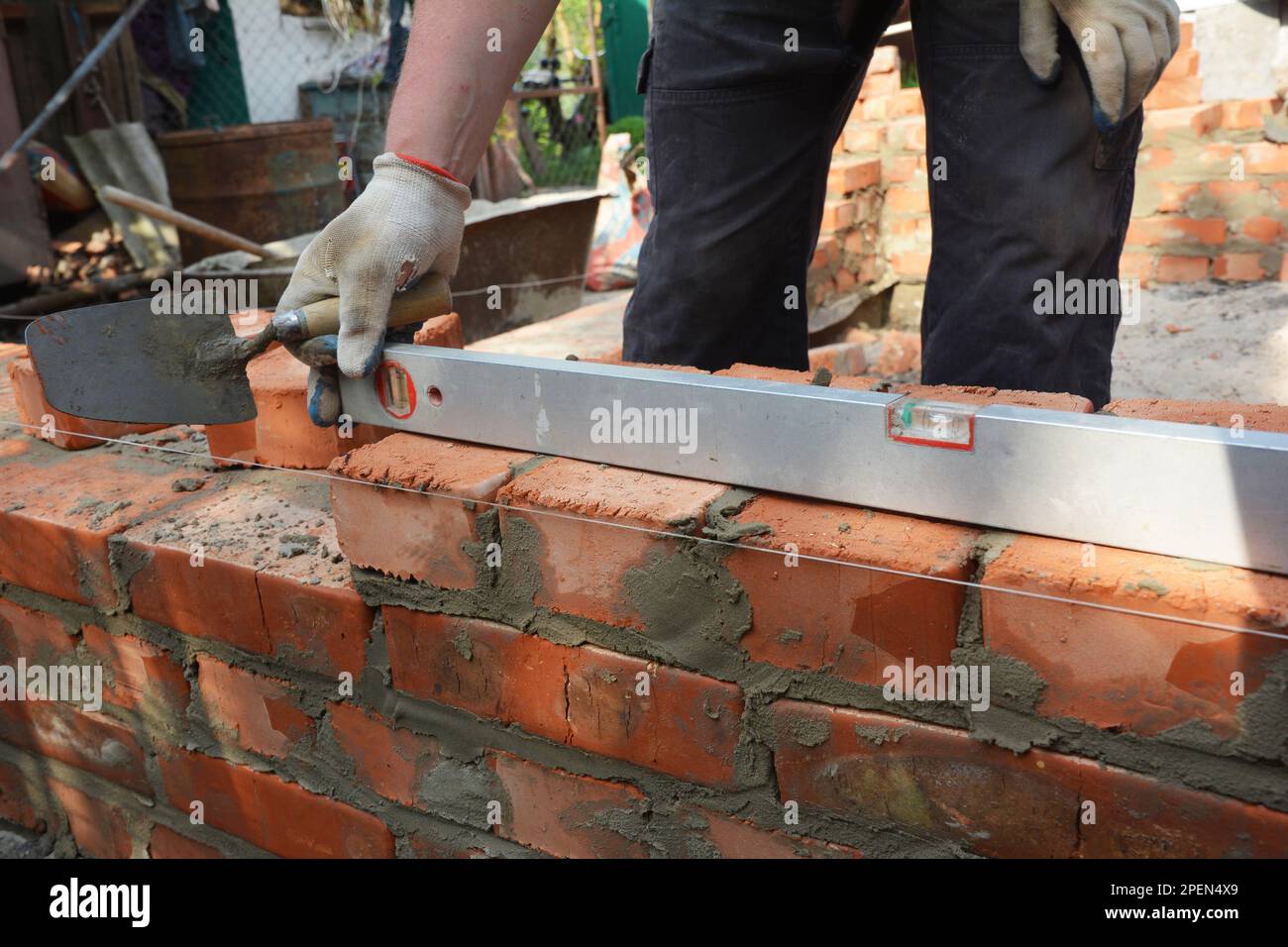 Builder contractor laying bricks and measure new house wall with spirit ...