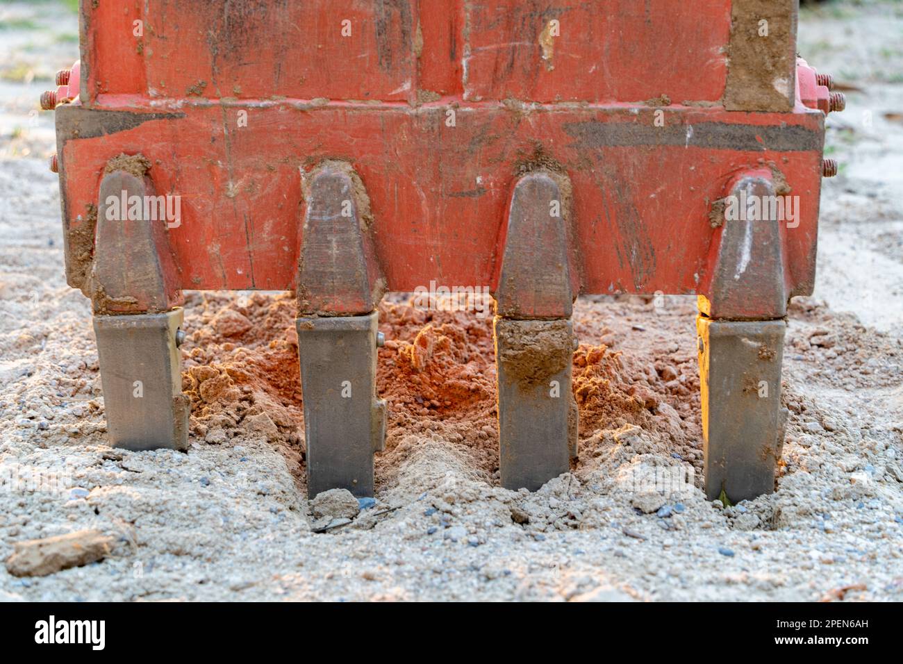 Close-up of an excavator bucket with rusty teeth digging the ground ...