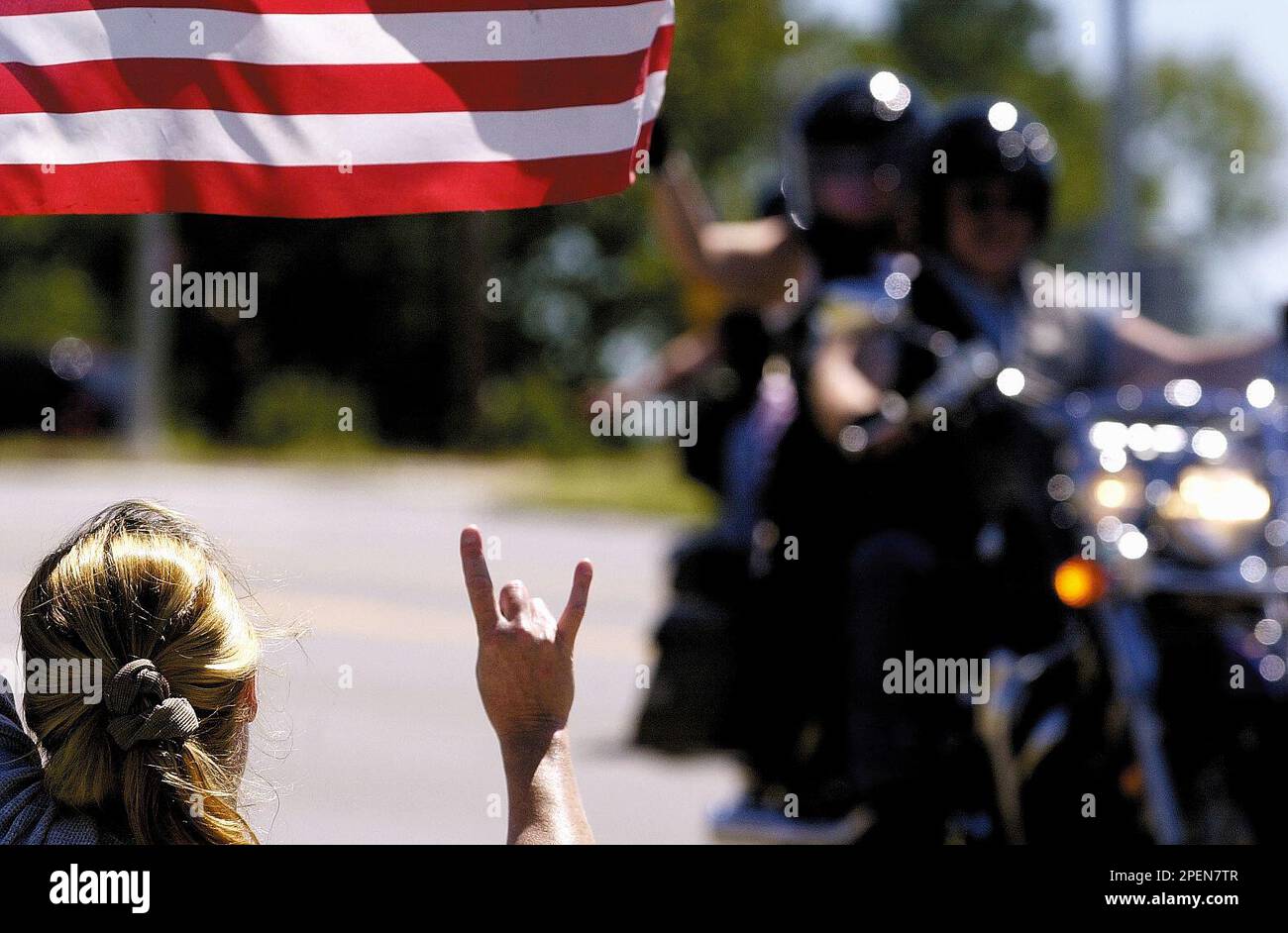 Tracy Davis, of Athens, Ala., waves her flag as motorcyclists drive by ...
