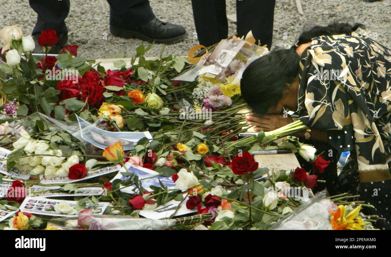 A woman offer prayers after placing a picture and flowers in a pool at ...
