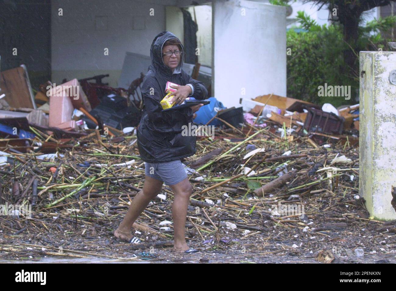 A Jamaican woman carries belongings after her house was destroyed by ...