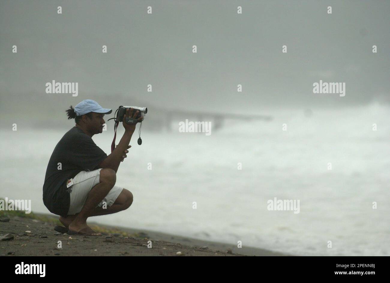 An unidentified Jamaican man films large waves in Kingston, Jamaica as ...