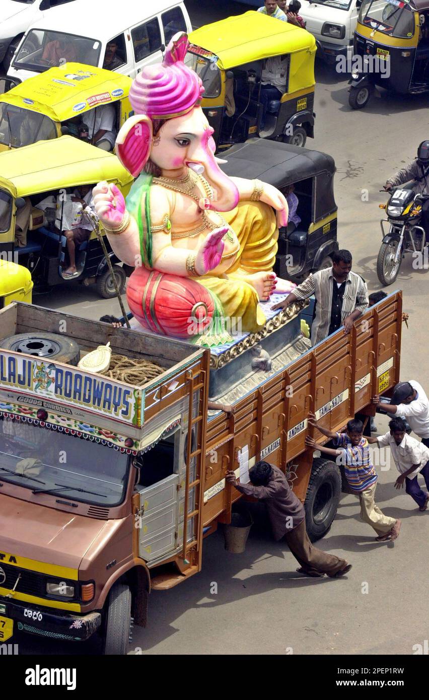 People push a truck, carrying an idol of the Hindu God Ganesha, that ...