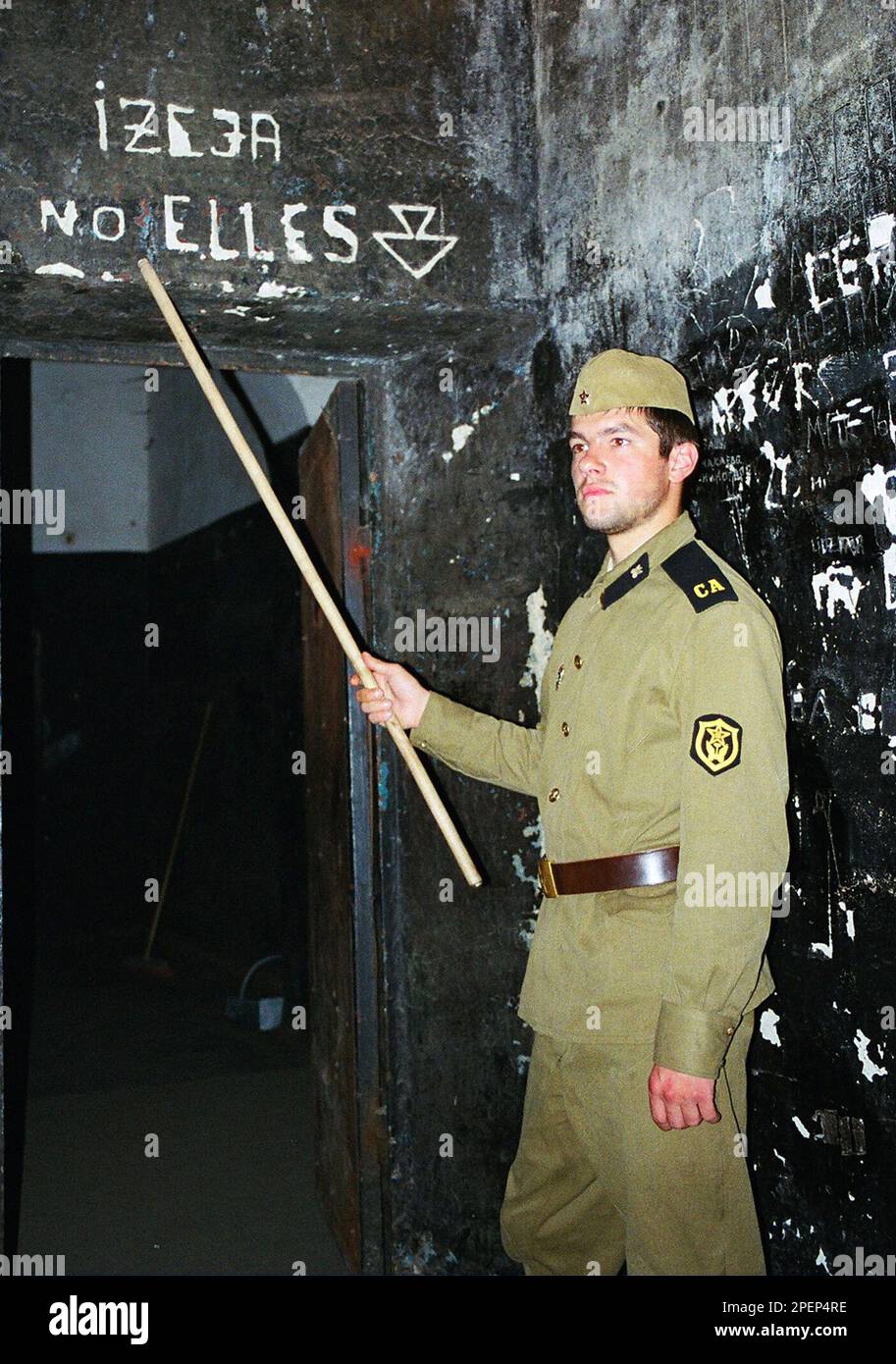 Jailor Vairis Zakitis points to a sign reading "You are leaving Hell ...