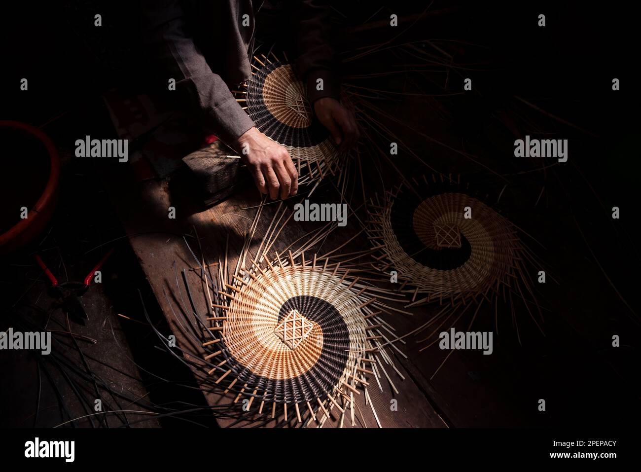 A craftsman uses peeled twigs to produce hand crafted basket at his ...