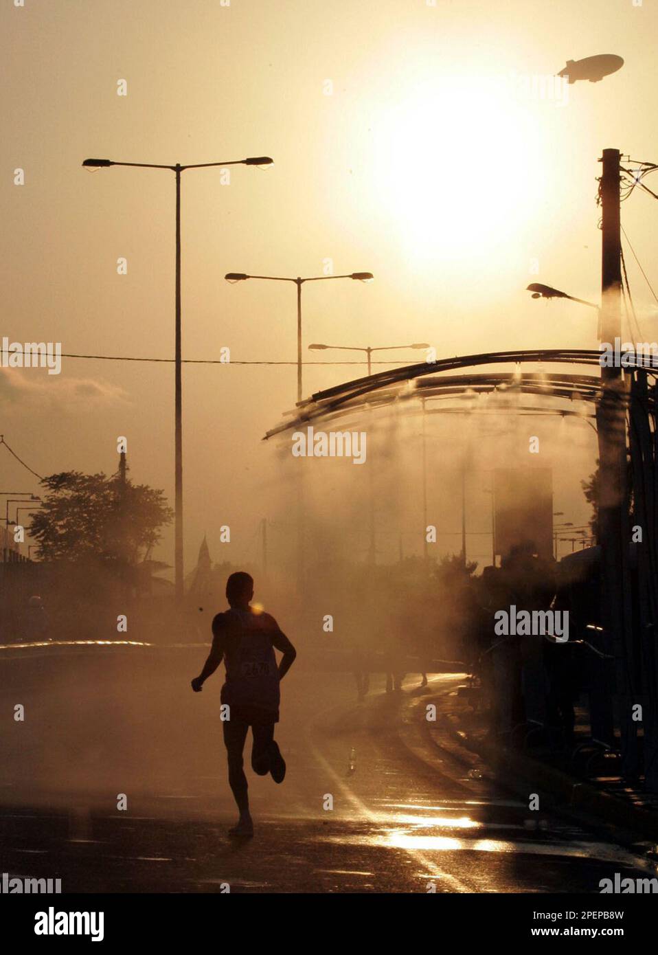 Waldemar Glinka of Poland runs through a shower during men's marathon ...