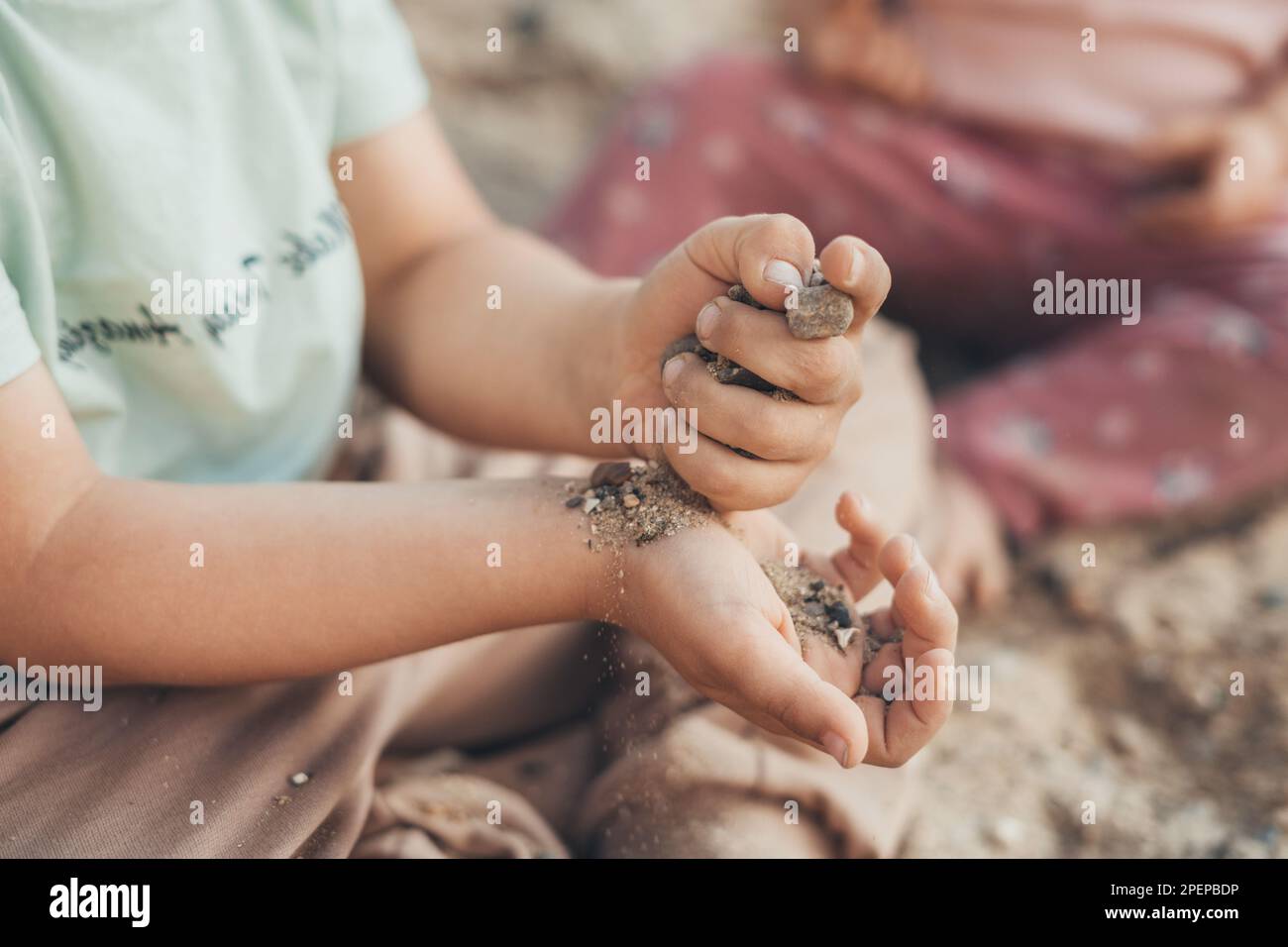 Close-up portrait of a child's hands holding little stones, playing ...