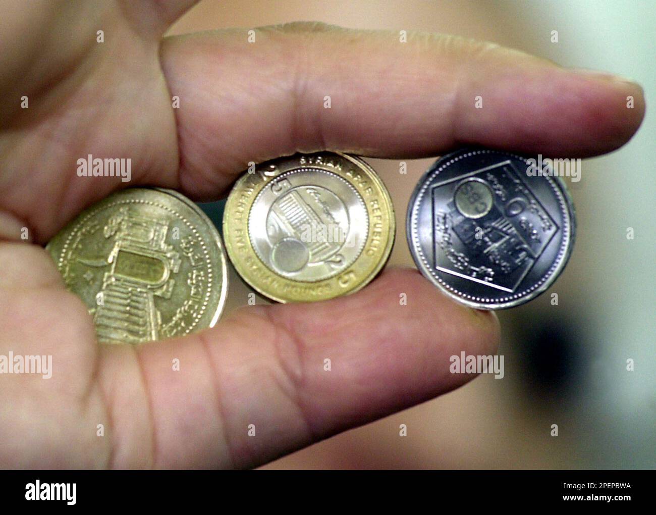 An official at the Central Bank of Syria displays three new coin ...