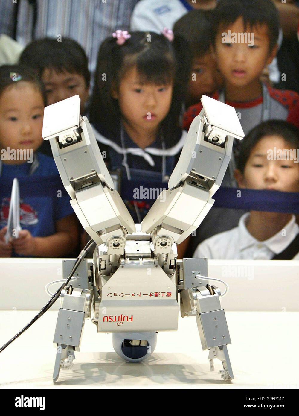 Children take a close look at a robot standing on its head during the ...