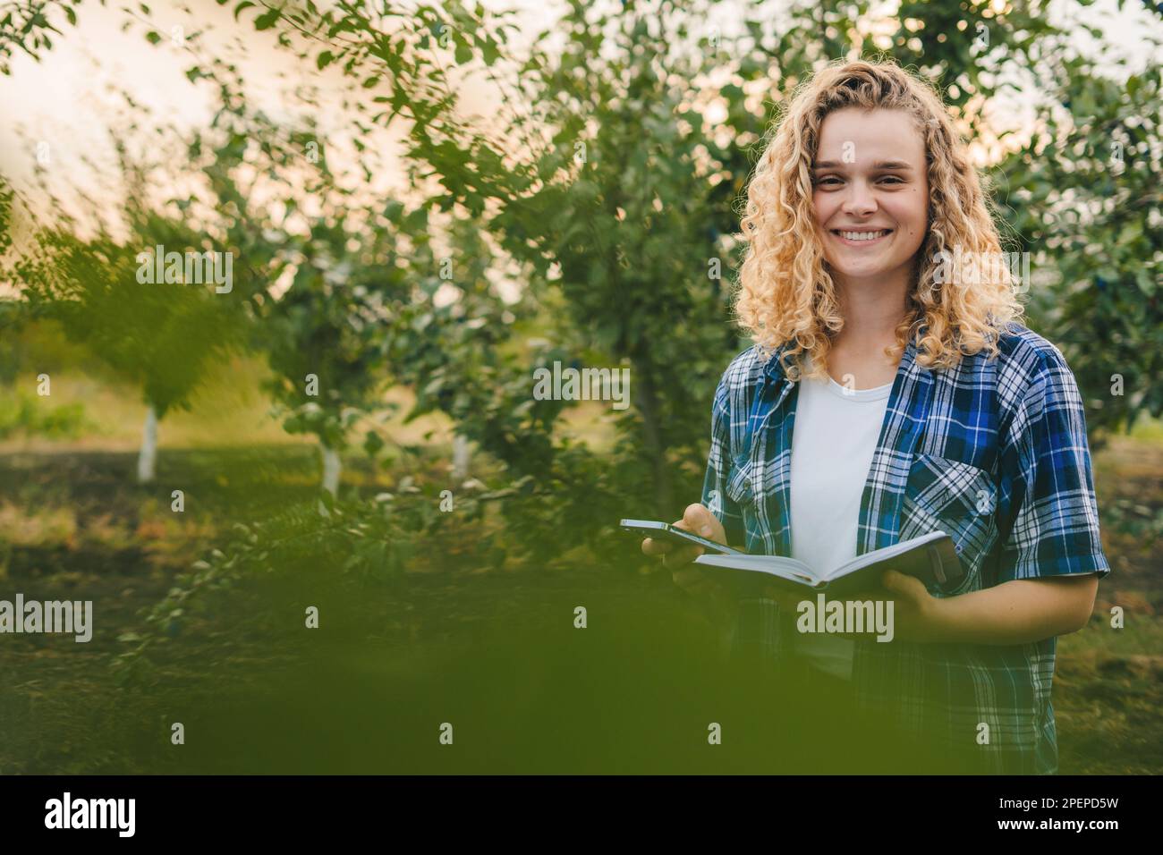 Caucasian young farmer with curly hair writing in a notebook about his ...