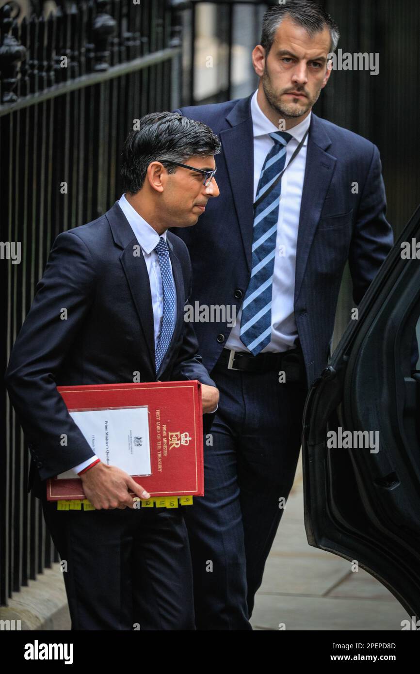 London, UK. 15th Mar, 2023. A tall ksecurity officer holds open the car dow for Rishi Sunak, MP ...