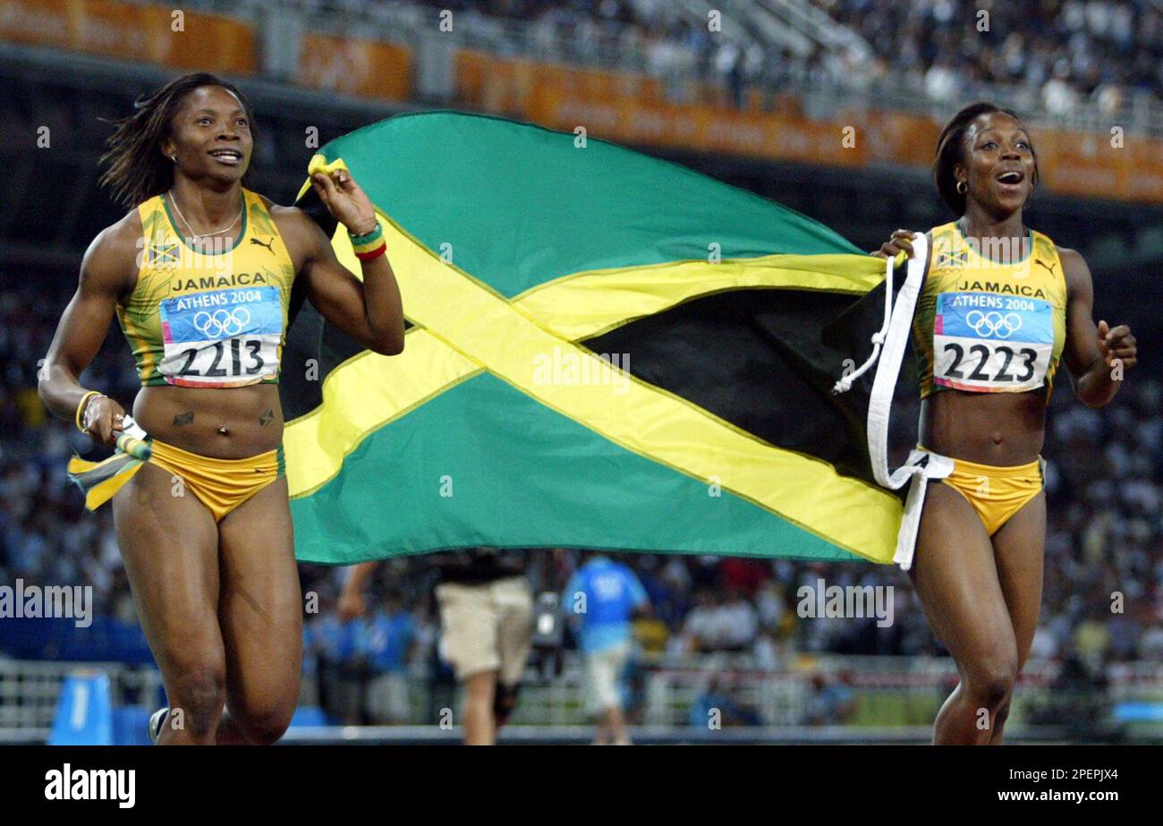 Jamaica's Veronica Campbell, right, carries a flag with compatriot ...