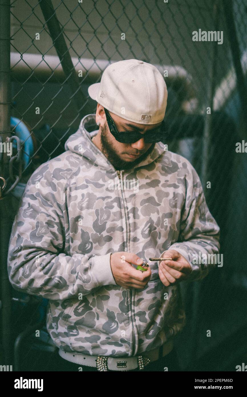 Cool looking man wearing sunglasses smoking a joint in the street ...