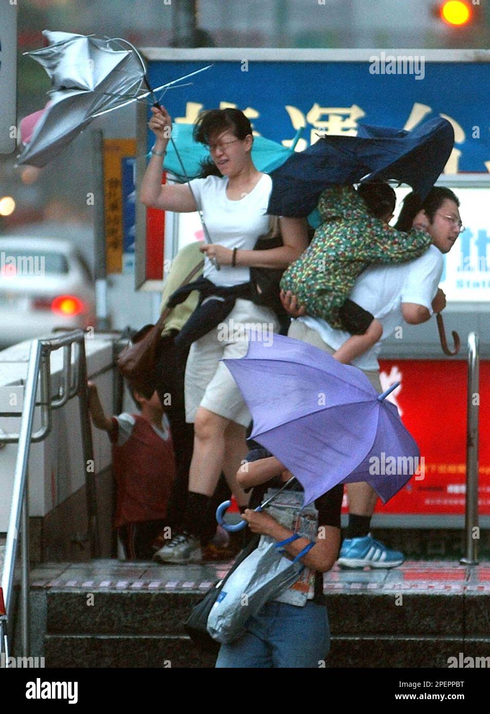 Pedestrians fight the winds of approaching Typhoon Aere Tuesday ...