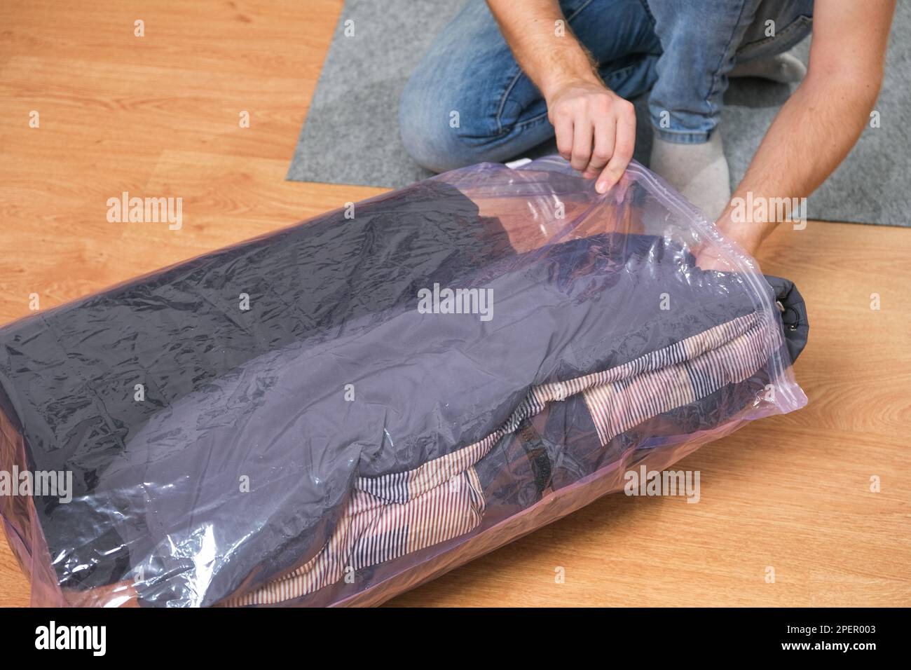 A man folds winter jackets and puts them in a vacuum bag for seasonal ...