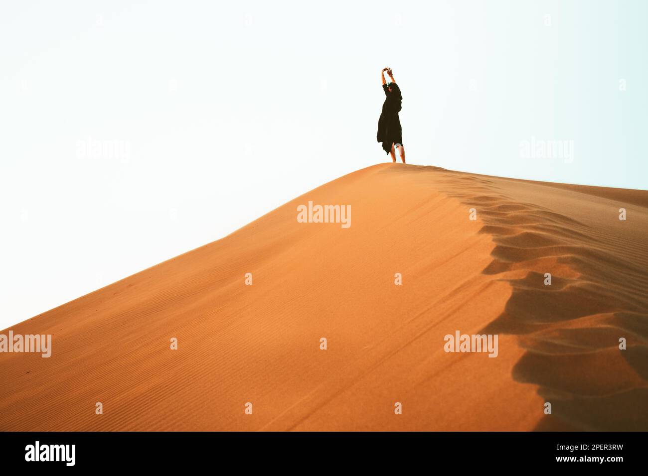 Woman enjoy sand dunes top in desert stretch arms pose . Travel ...