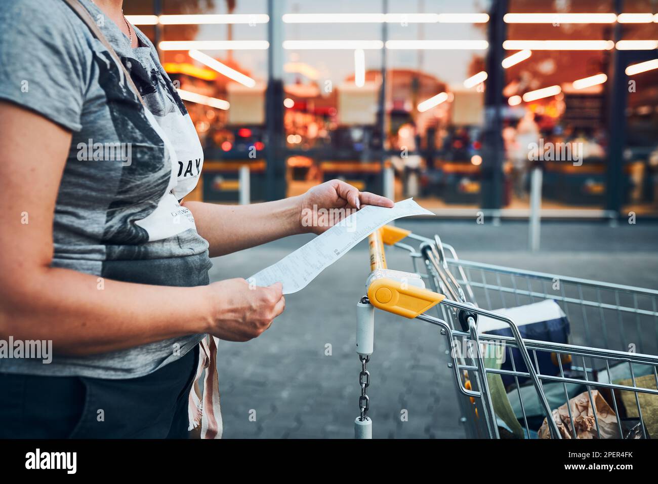 Woman looking at higher prices on receipt after shopping in grocery ...